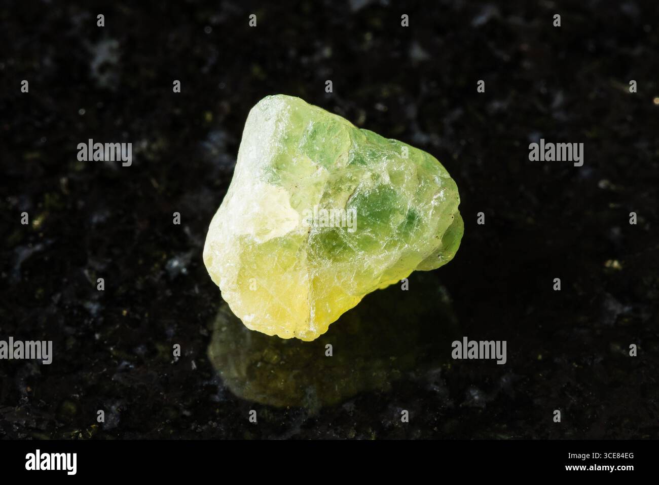 sample of rough yellow green sapphire corundum rock on black granite ...