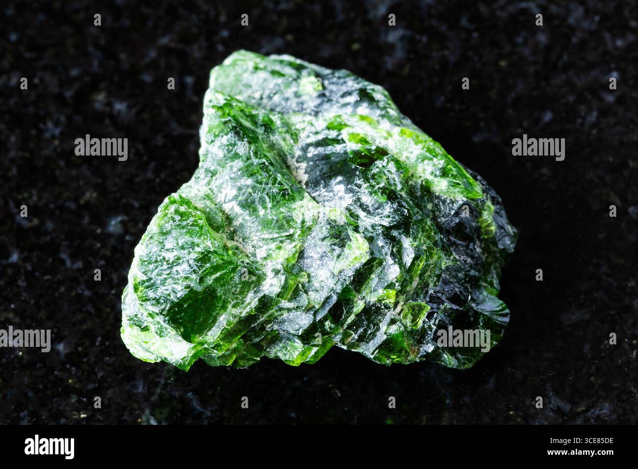 sample of rough chrome diopside mineral on black granite background ...