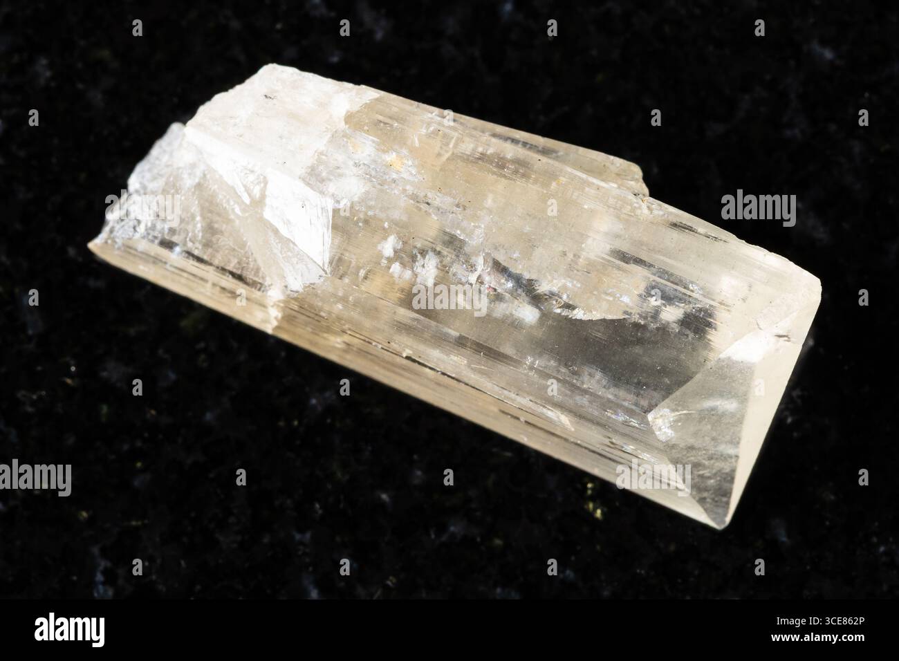 sample of rough danburite mineral on black granite background close up ...
