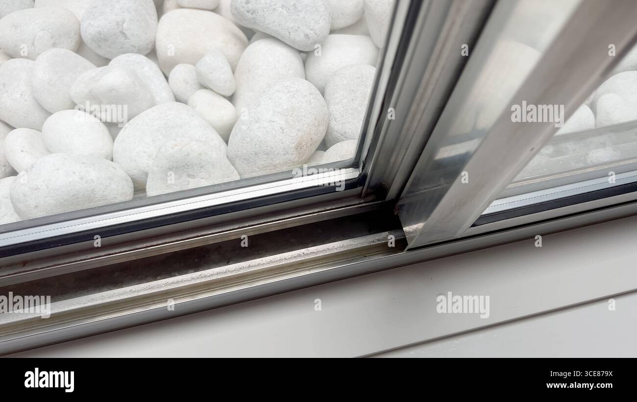 Angled view of a basement window frame looking outside at a bed of ...