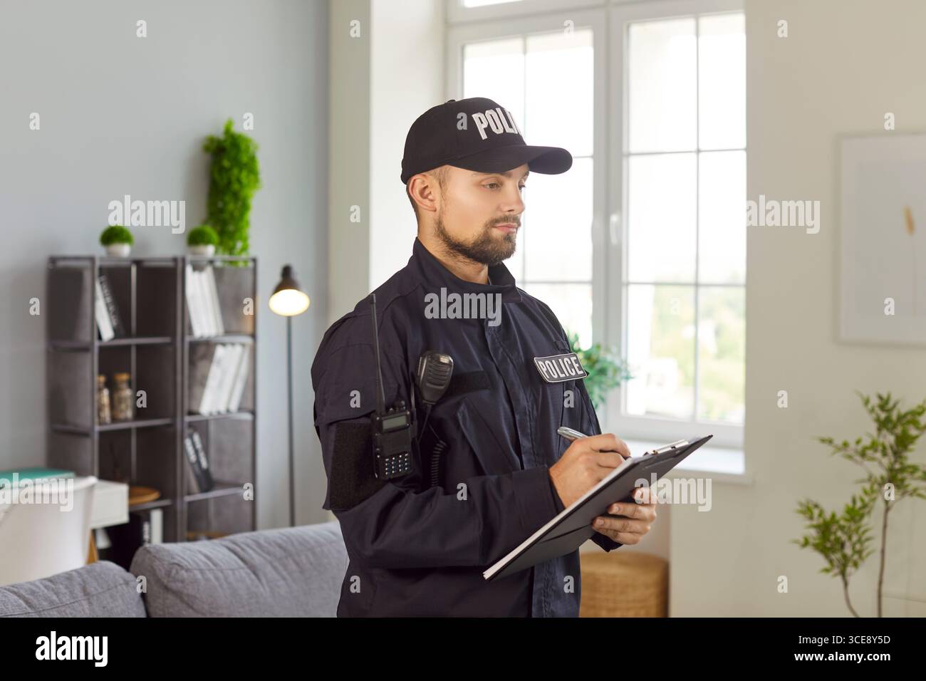 Police officer writing report during home investigation visit Stock ...