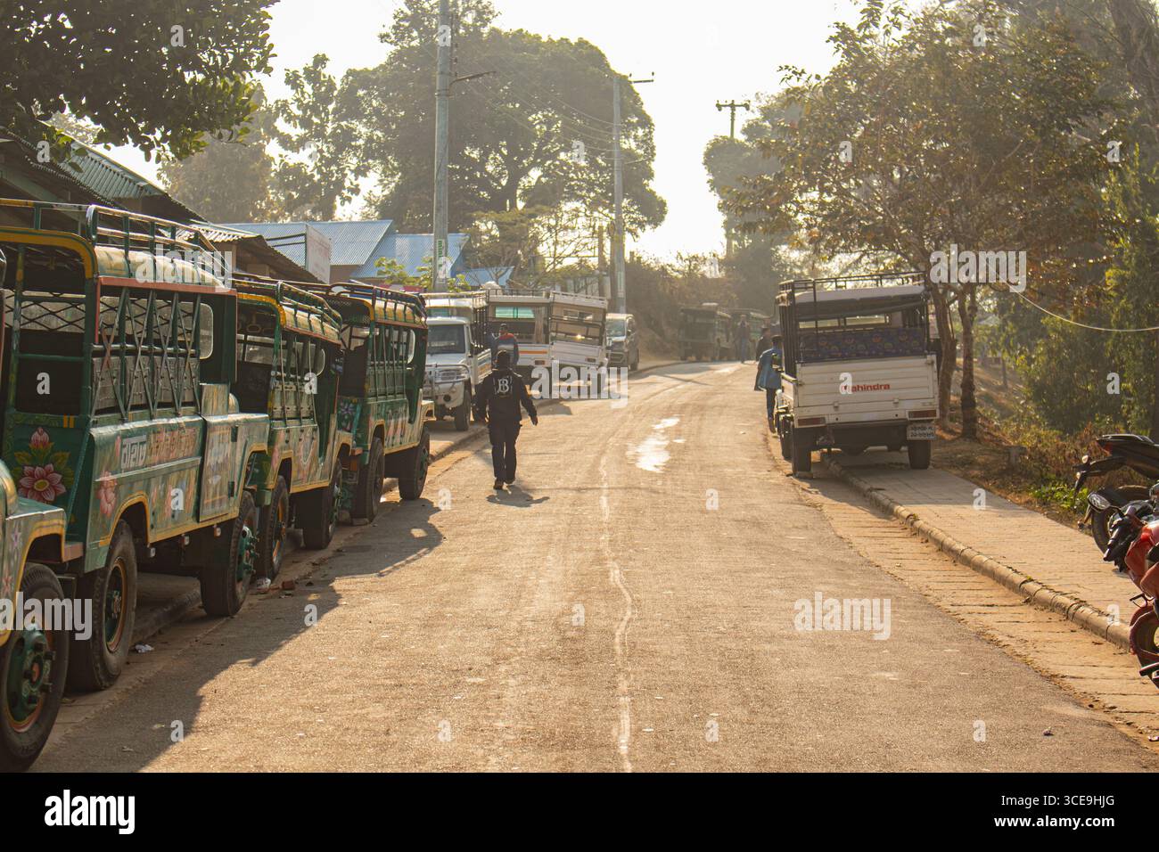 A quiet morning street in Sajek Valley lined with colorful local jeeps and small trucks Stock ...