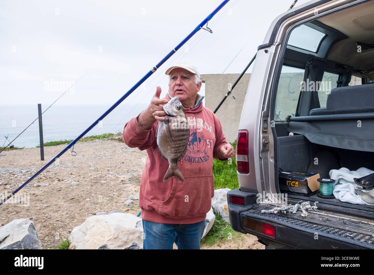 Portuguese fisherman proudly showing the fish he caught from the cliffs ...