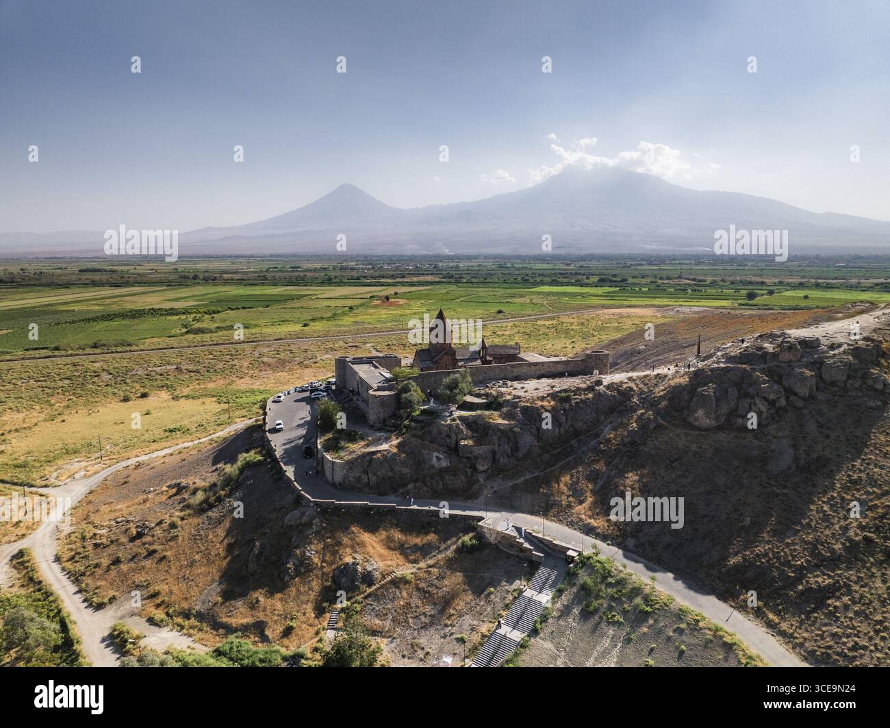 Aerial view of ancient monastery atop a hill, shadowed by distant, snow ...