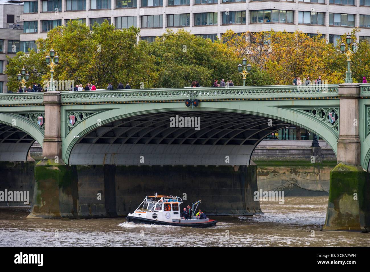Small work boat going under the Westminster Bridge with Saint Thomas ...