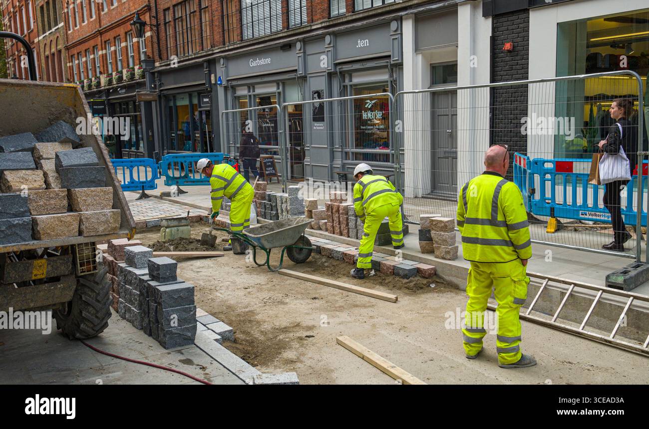Male construction workers in high visibility green uniforms installing ...