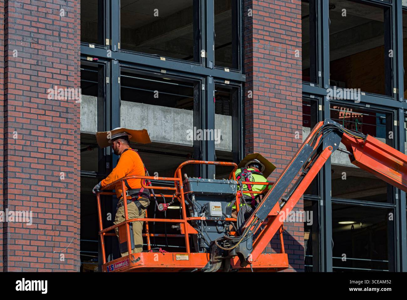 Male construction workers working from articulating hydraulic boom lift ...