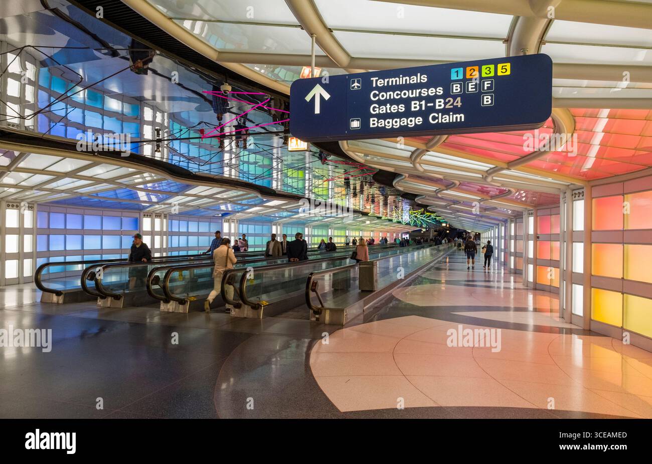 Passengers walking in tunnel illuminated with a neon installation ...