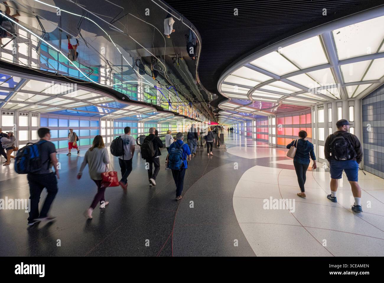 Passengers walking in tunnel illuminated with a neon installation ...