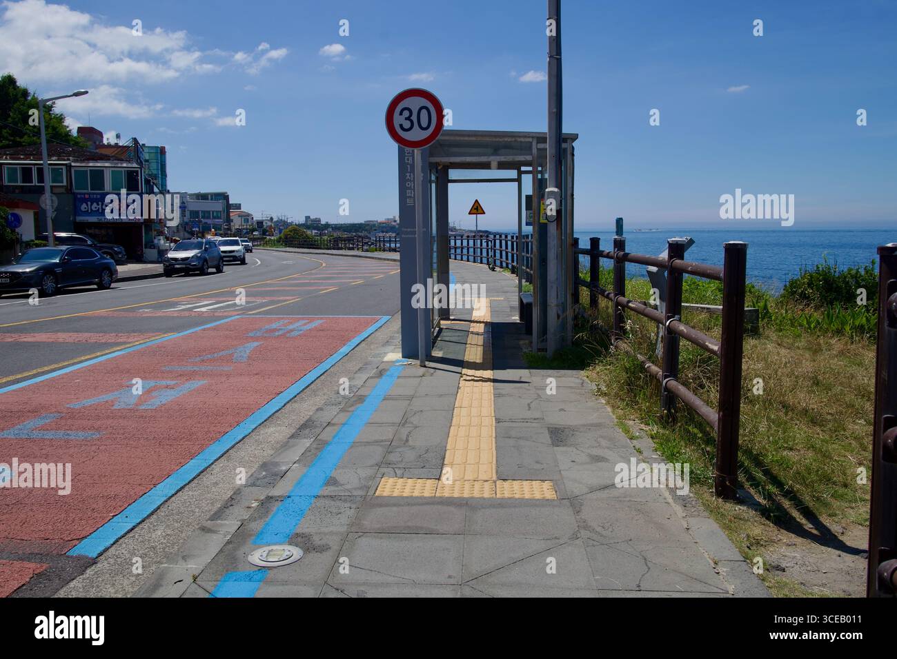 A small bus stop shelters the seaside sidewalk beside the Hagu‑Aewol ...