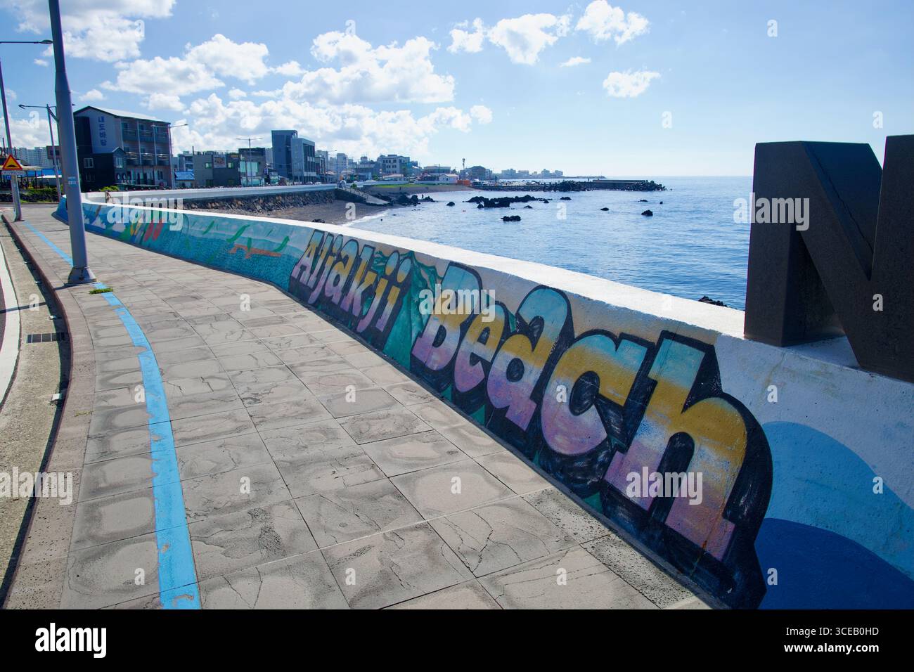 Lettering on the Aljakji Beach seawall faces the rocky shoreline along ...