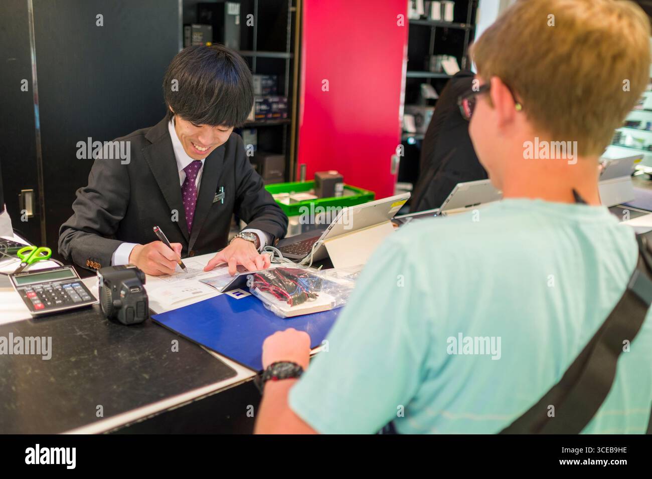 Man working behind counter filling out paperwork for a camera exchange ...