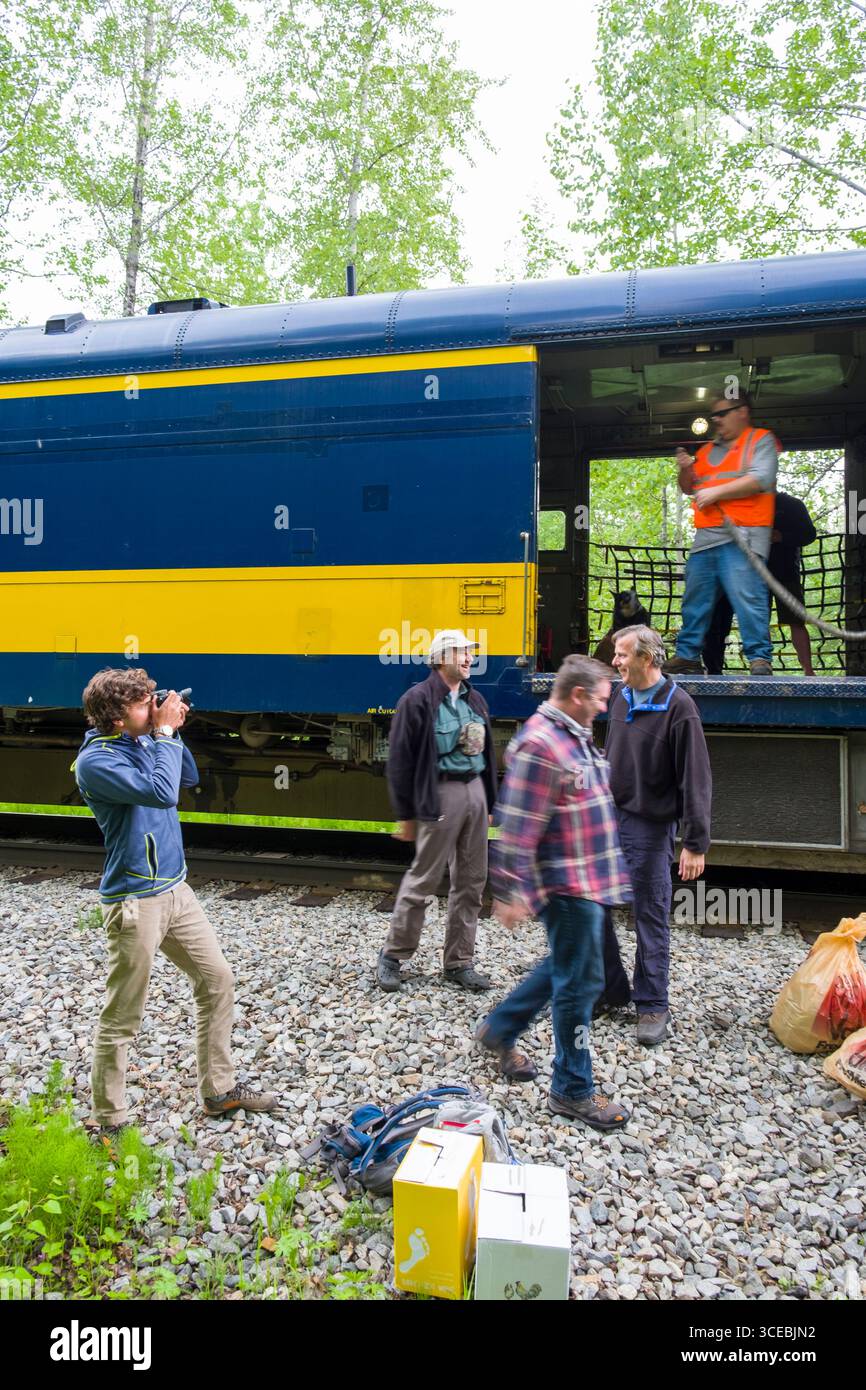 Men standing on the side of freight carriage of the Alaska Railroad ...