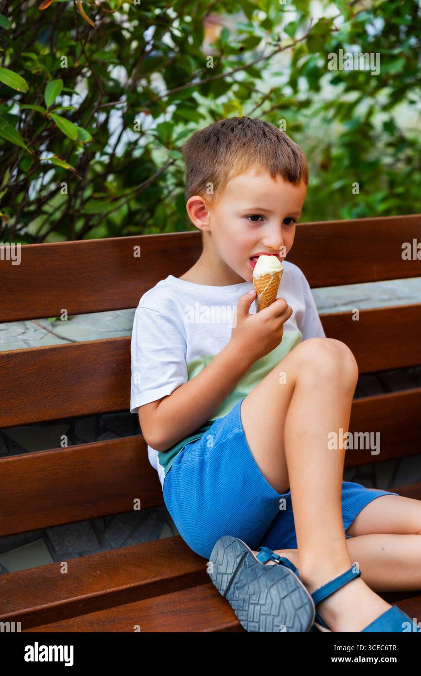 Child enjoying ice cream cone on park bench Stock Photo - Alamy