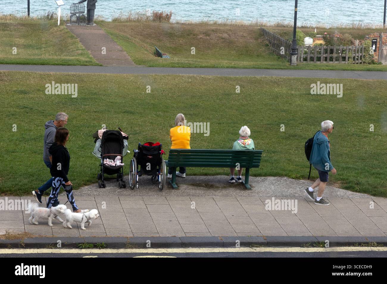 People sitting on a bench and walking by in Whitby, North Yorkshire ...