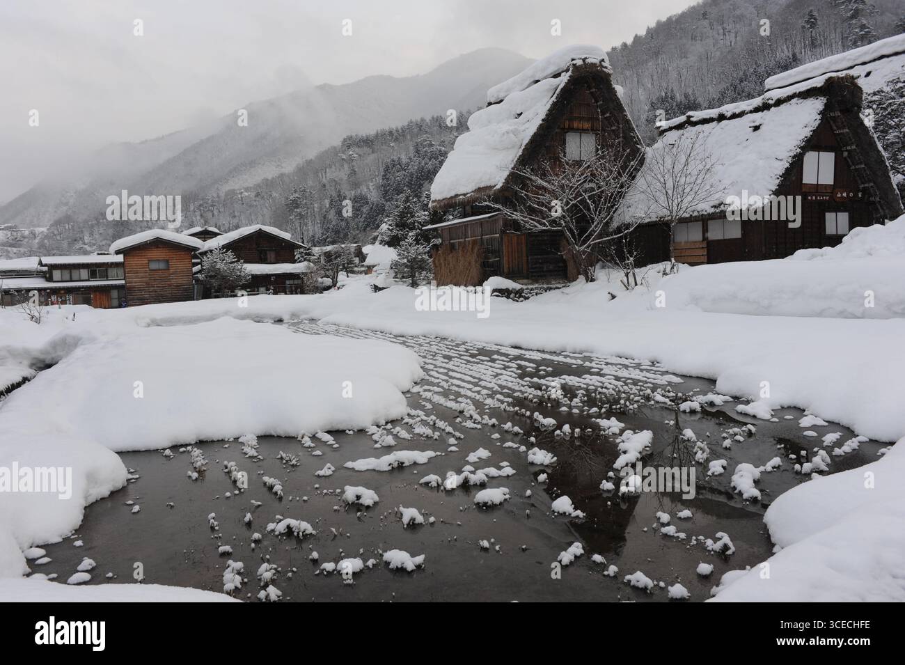 Thatched roof house covered in snow in winter in a mountain valley in ...