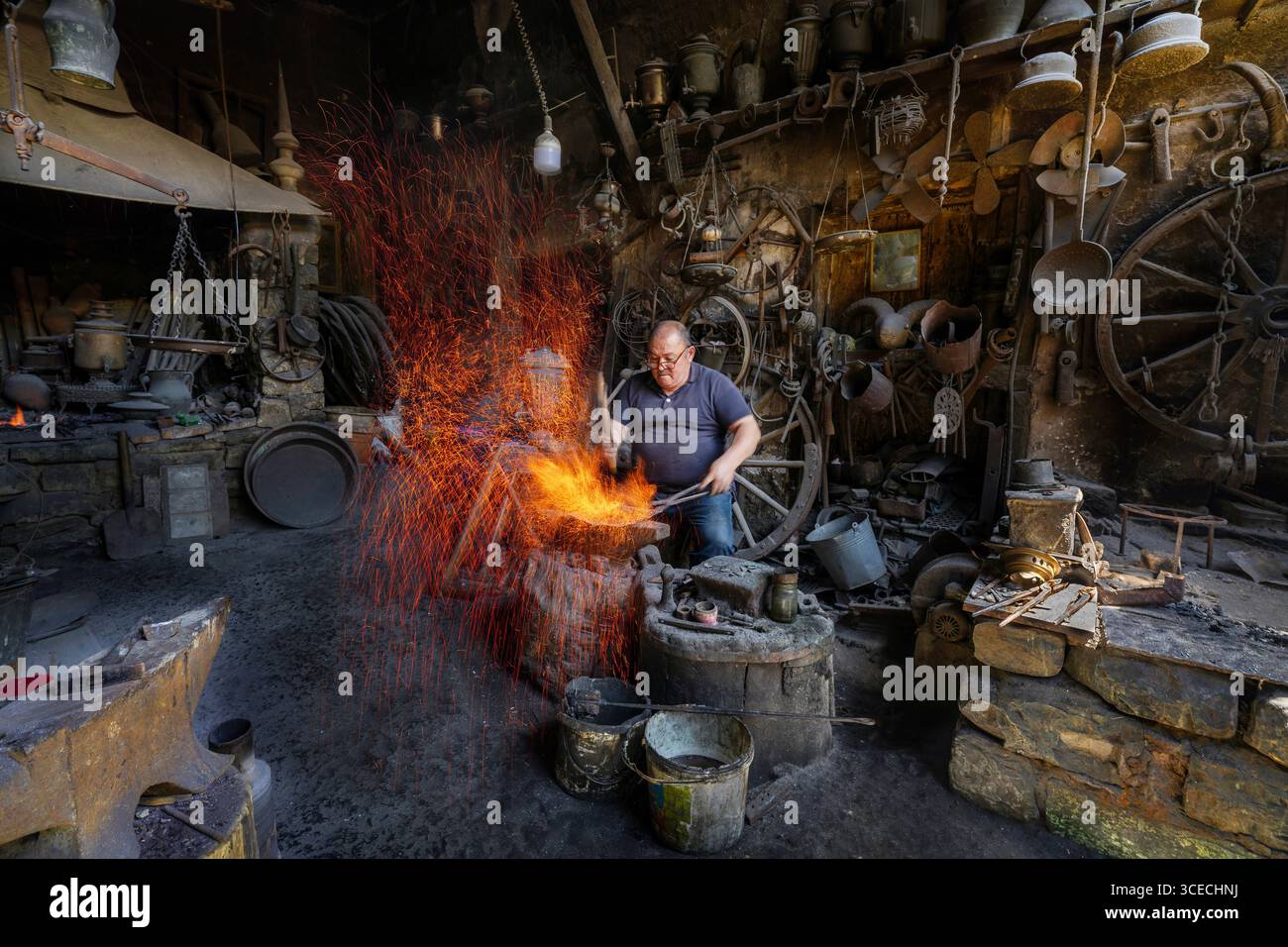 Copper craftsman hammers the heated copper in his workshop in Lahic ...