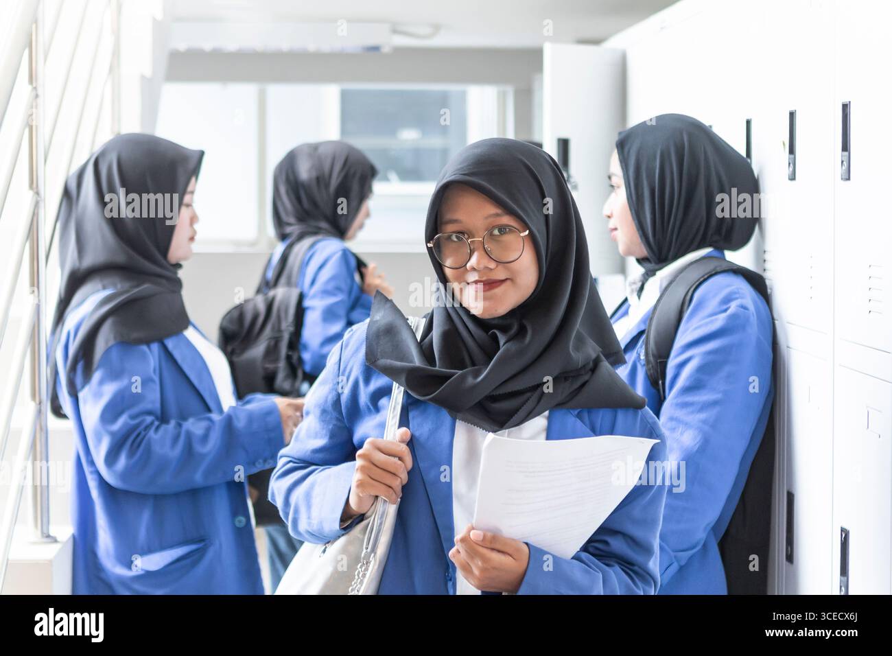 A group of Muslim students in blue uniforms and hijabs gathers in a ...