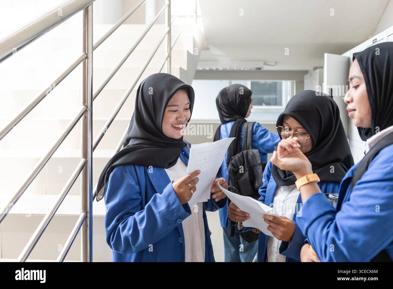 Asian Muslim students in hijabs engage in a lively discussion, holding ...