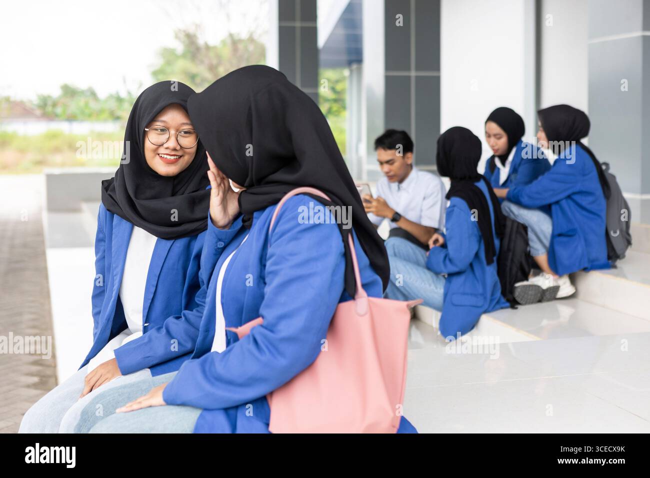 A group of Asian Muslim students wearing hijabs and blue uniforms ...