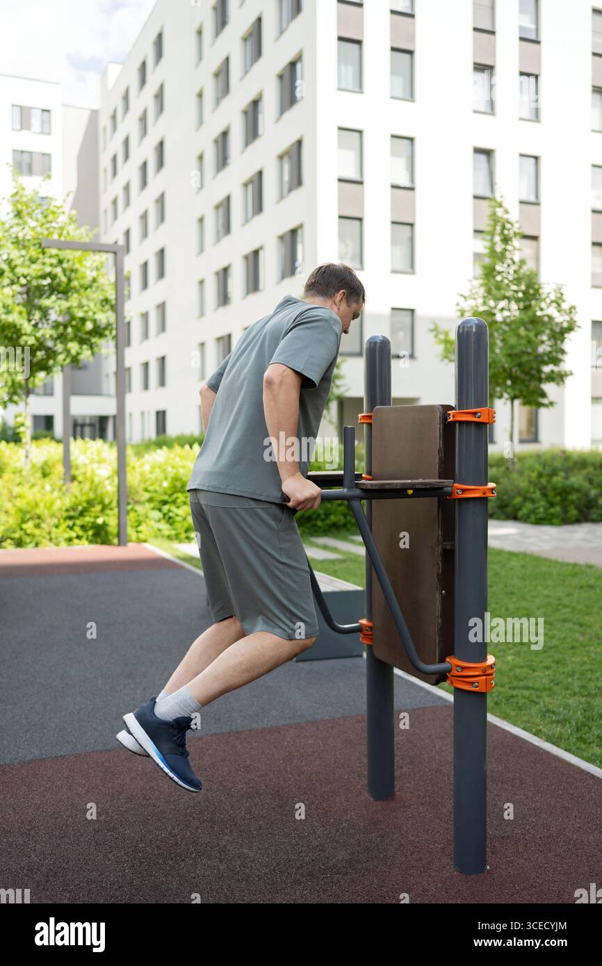 A man performs an outdoor exercise routine using dip bars in a peaceful ...