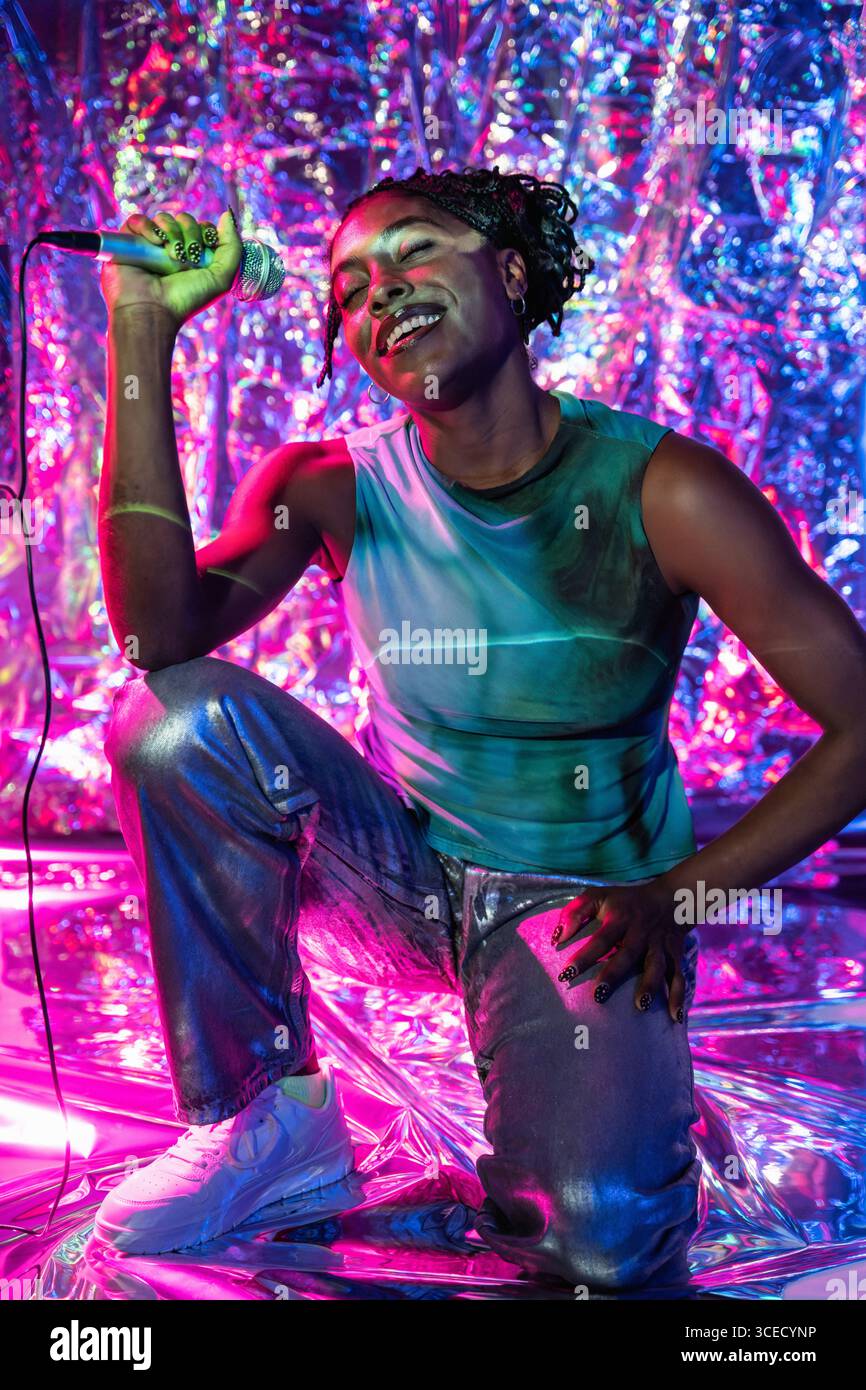 A dynamic black singer passionately kneels with a microphone against a ...