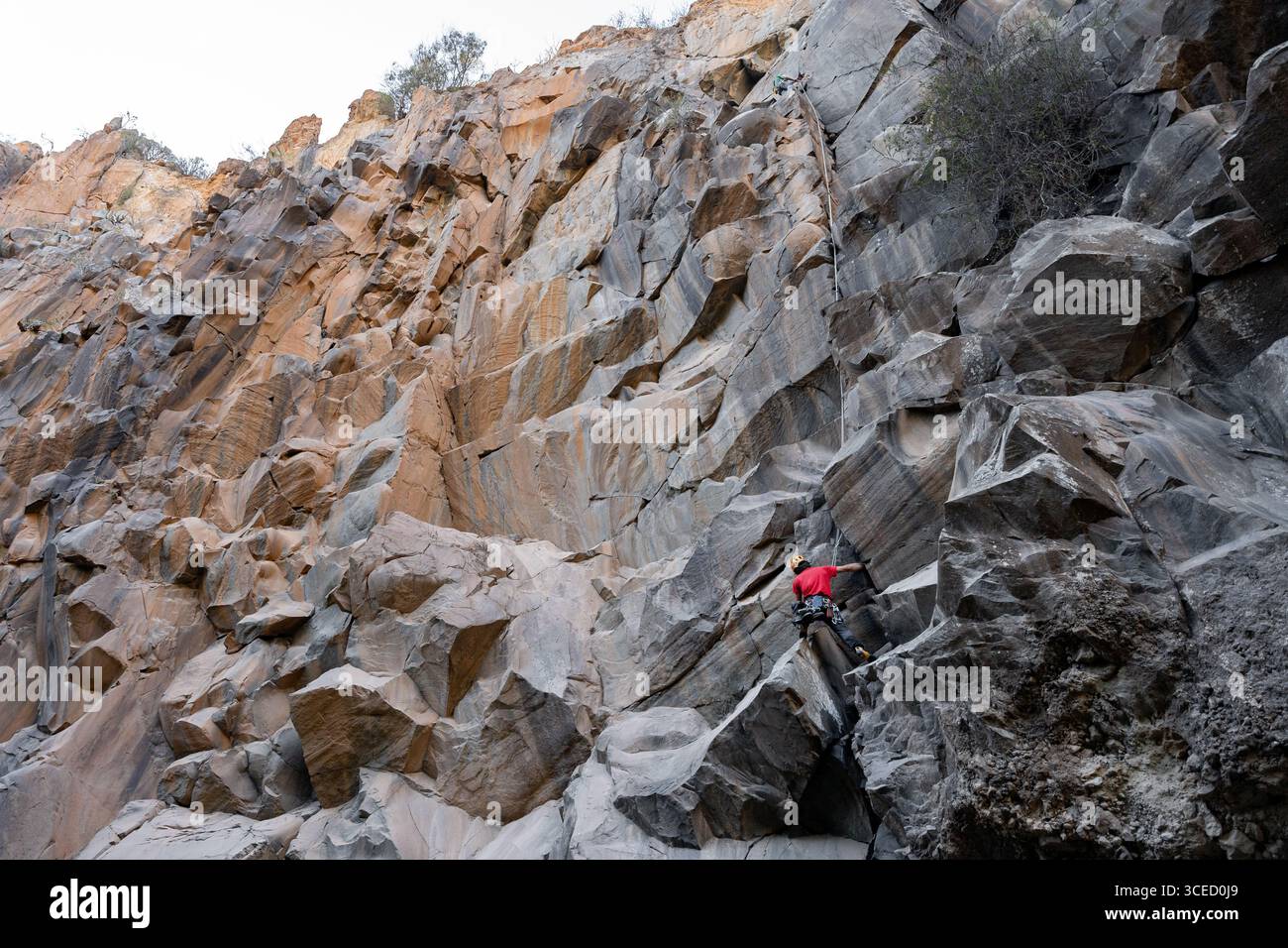 Two climbers tackles a challenging ascent on a rugged rock face ...