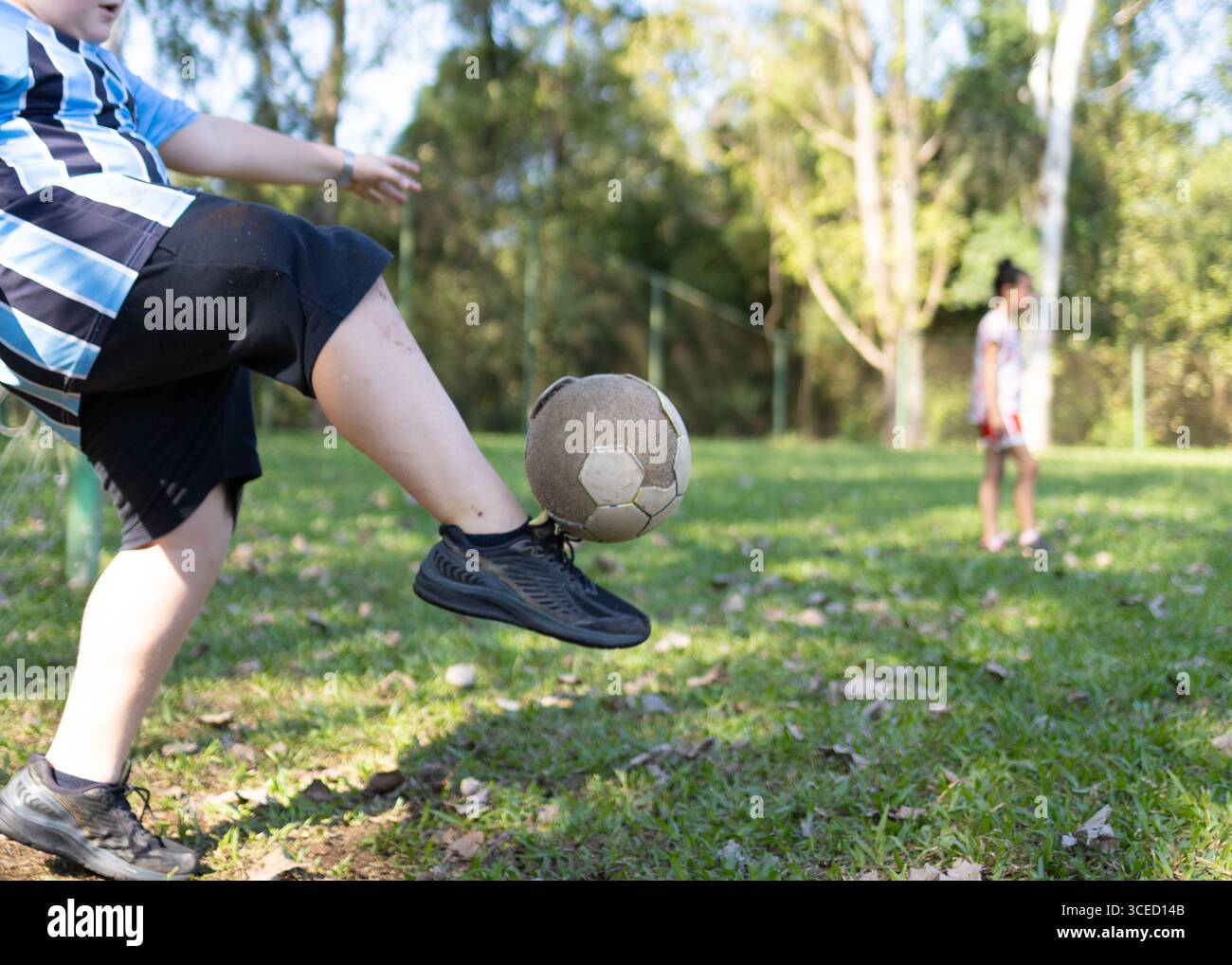 Cropped unrecognizable Brazilian children play soccer on a lush grass ...