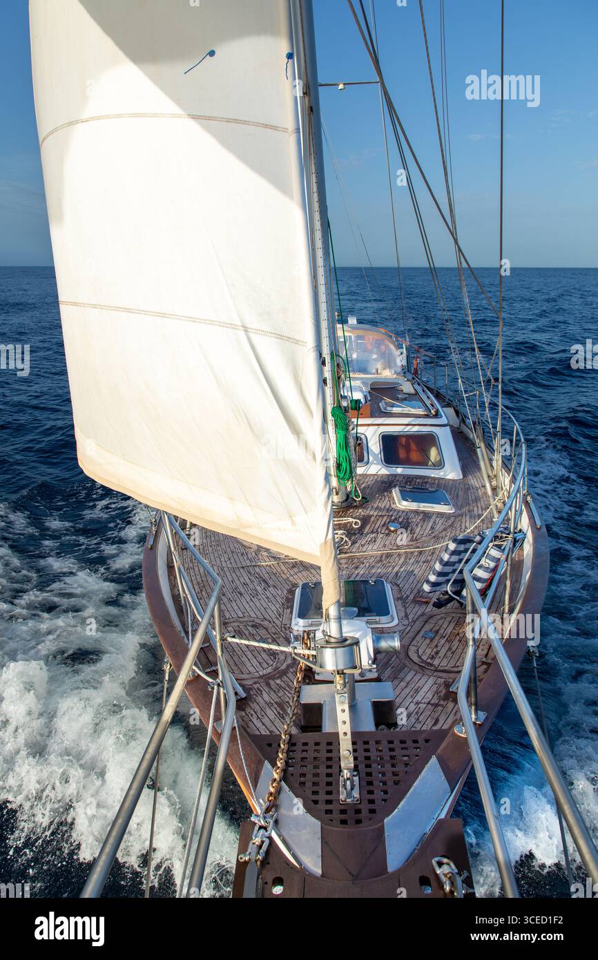 A sleek yacht sails through the Mediterranean waters, its sail full and ...