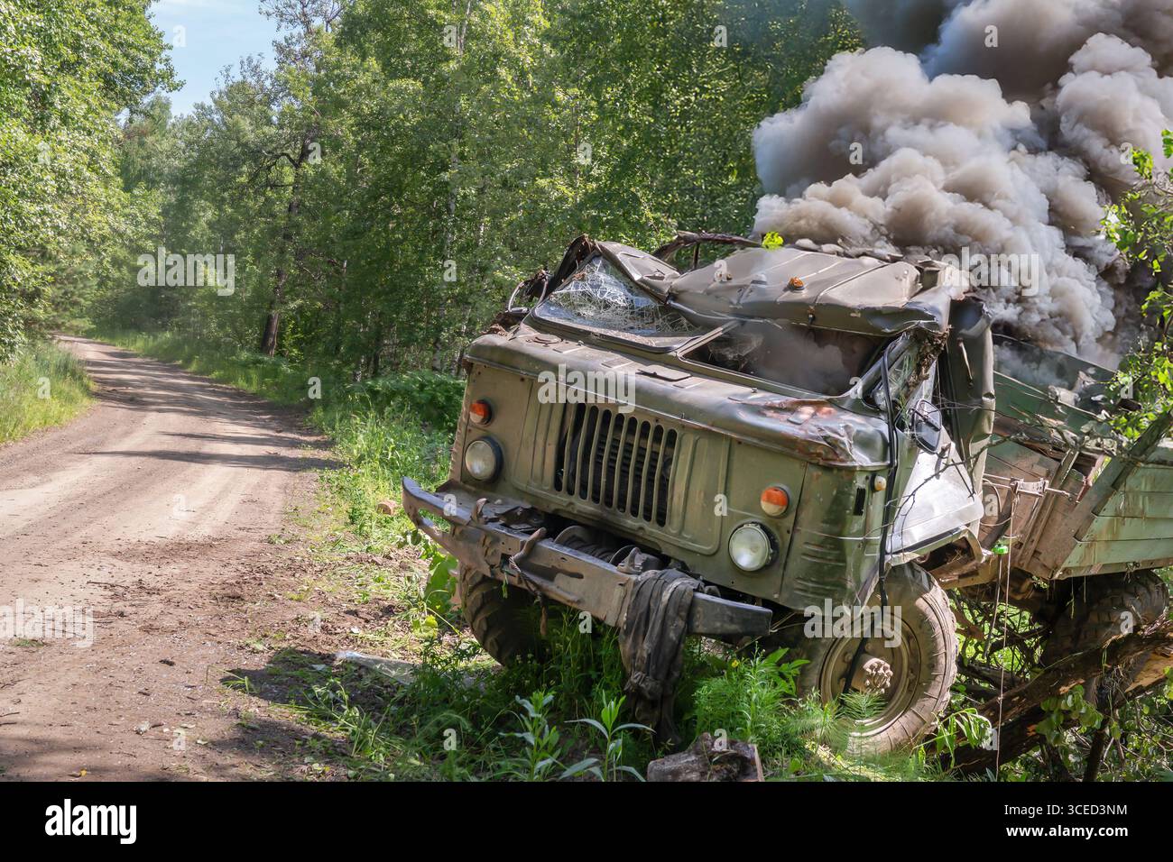 Damaged military truck stands abandoned on a dirt road, emitting thick ...