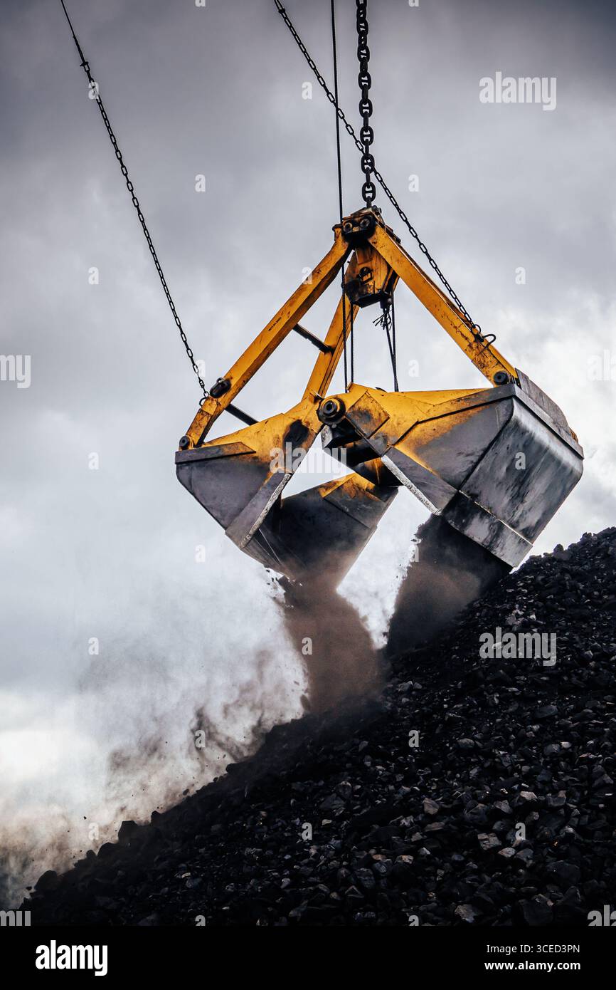 A large coal bucket suspended from a robust crane is seen in action at ...