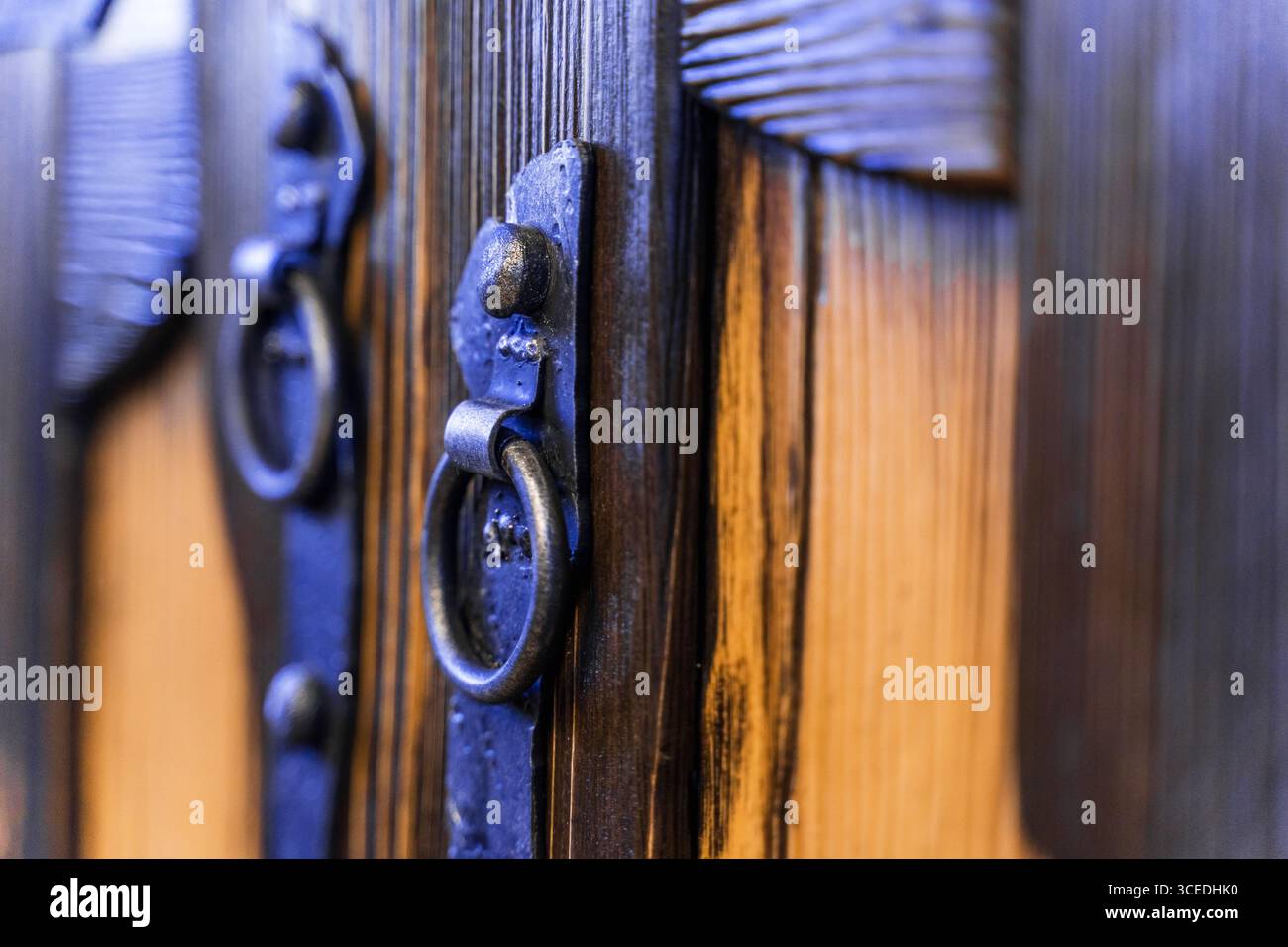 A wooden door with a black metal latch. The latch is attached to the ...