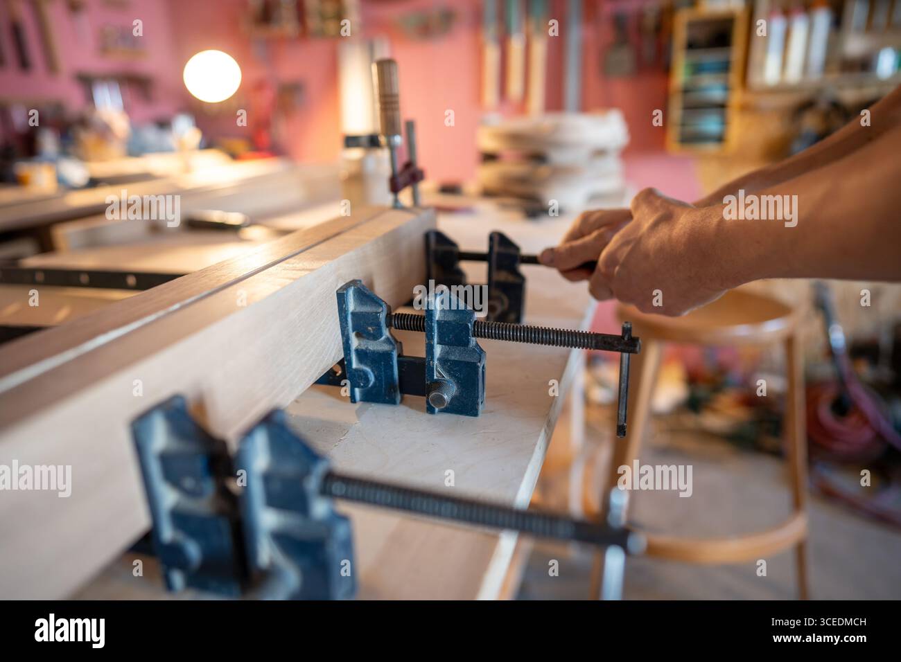 Craftsman secure glued wood blocks with clamps to form thick board ...