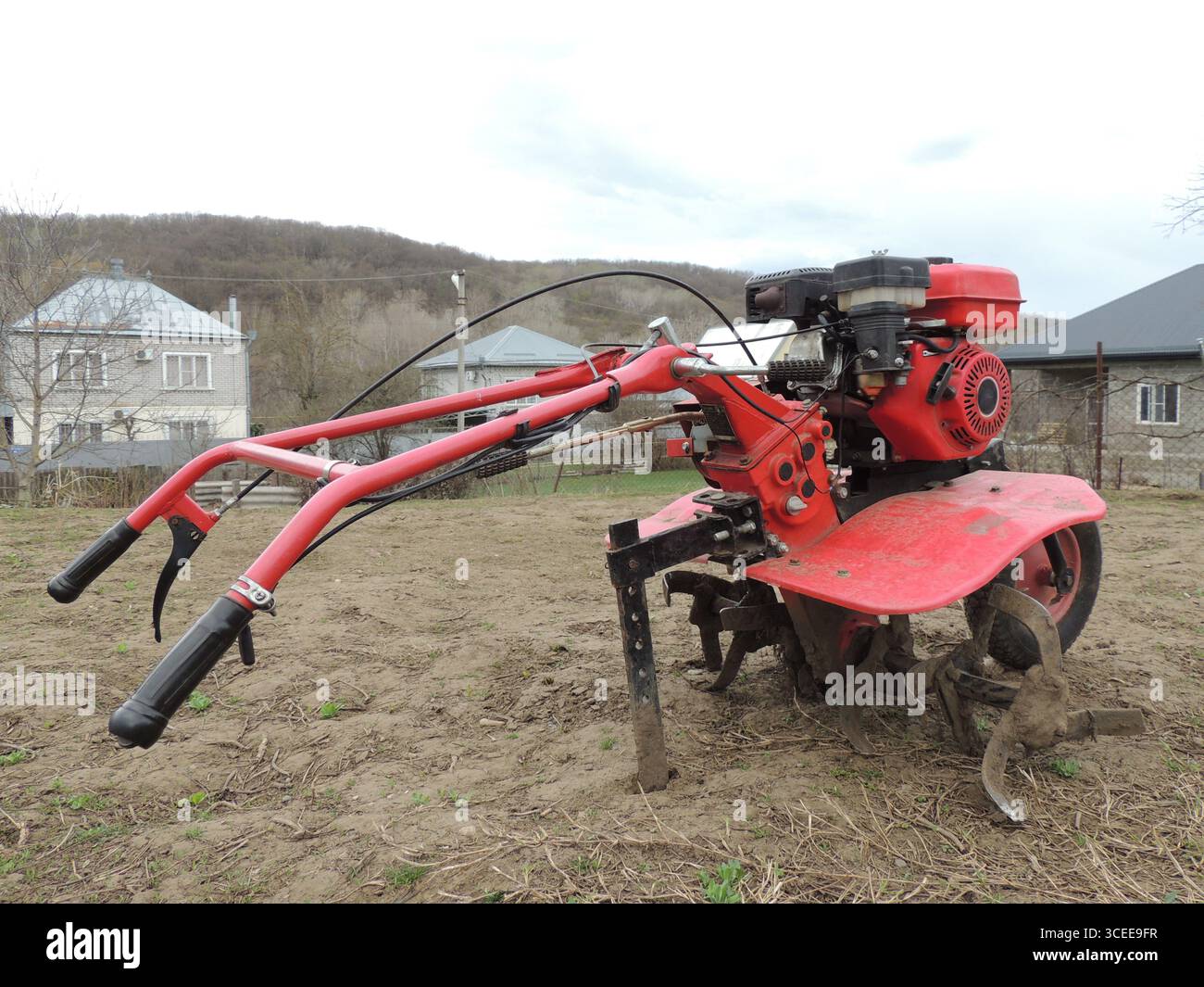 red hand petrol plow standing on farm land with dry grass against ...