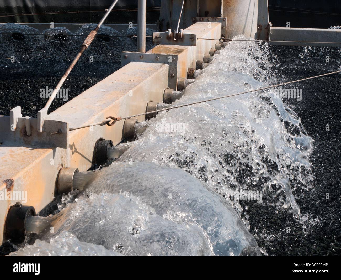 detail of the arm of a tricking filter with water flowing in a waste ...
