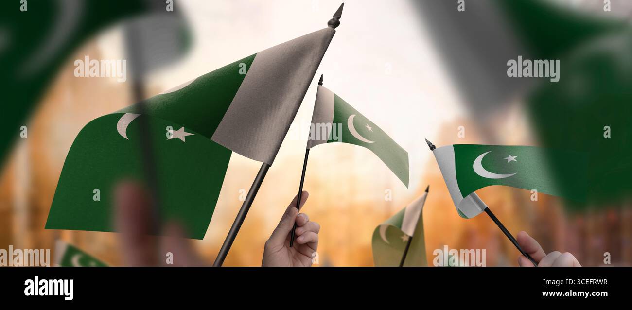 Pakistan flags in their hands on a blurred urban background. The photo ...