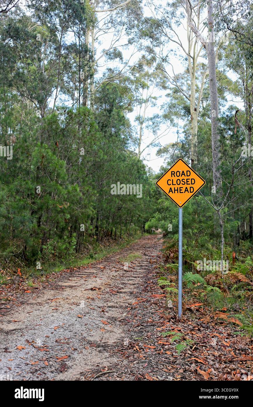 Road closed ahead safety sign on a lonely rural dirt road; vertical ...