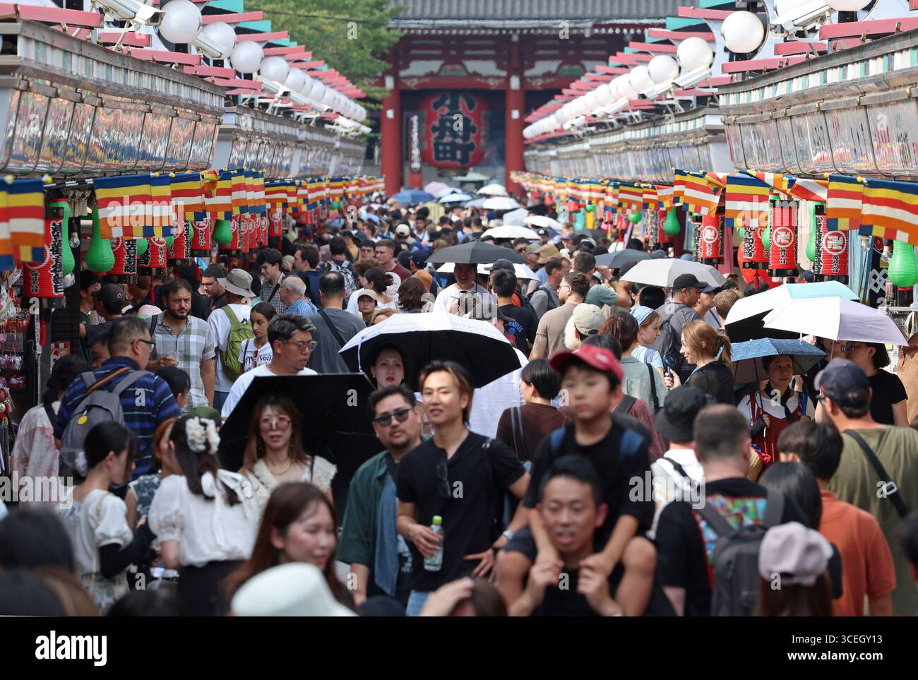 People walk during the intense heat at Asakusa district in Taito Ward ...