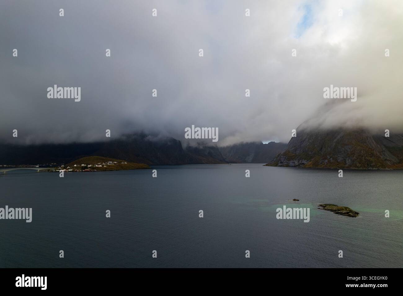 Aerial view of a tranquil fjord embraced by towering cliffs shrouded in ...