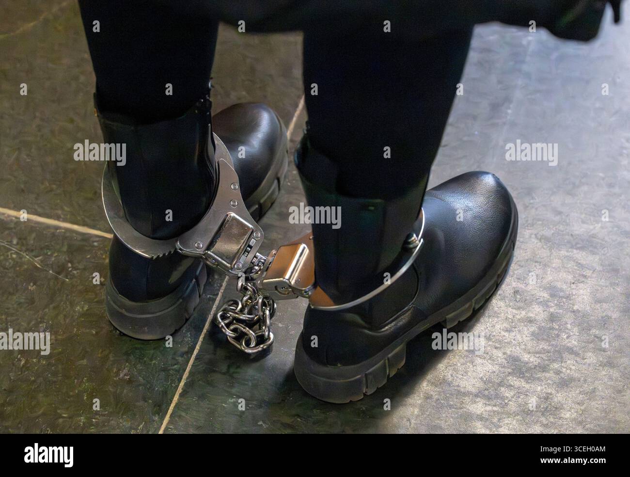 18 August 2025, Bavaria, Traunstein: The defendant wears shackles ...