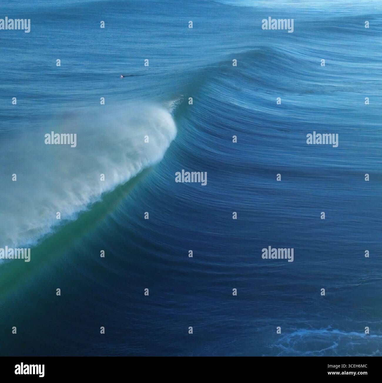 Aerial view of a powerful ocean wave cresting with frothy white foam ...