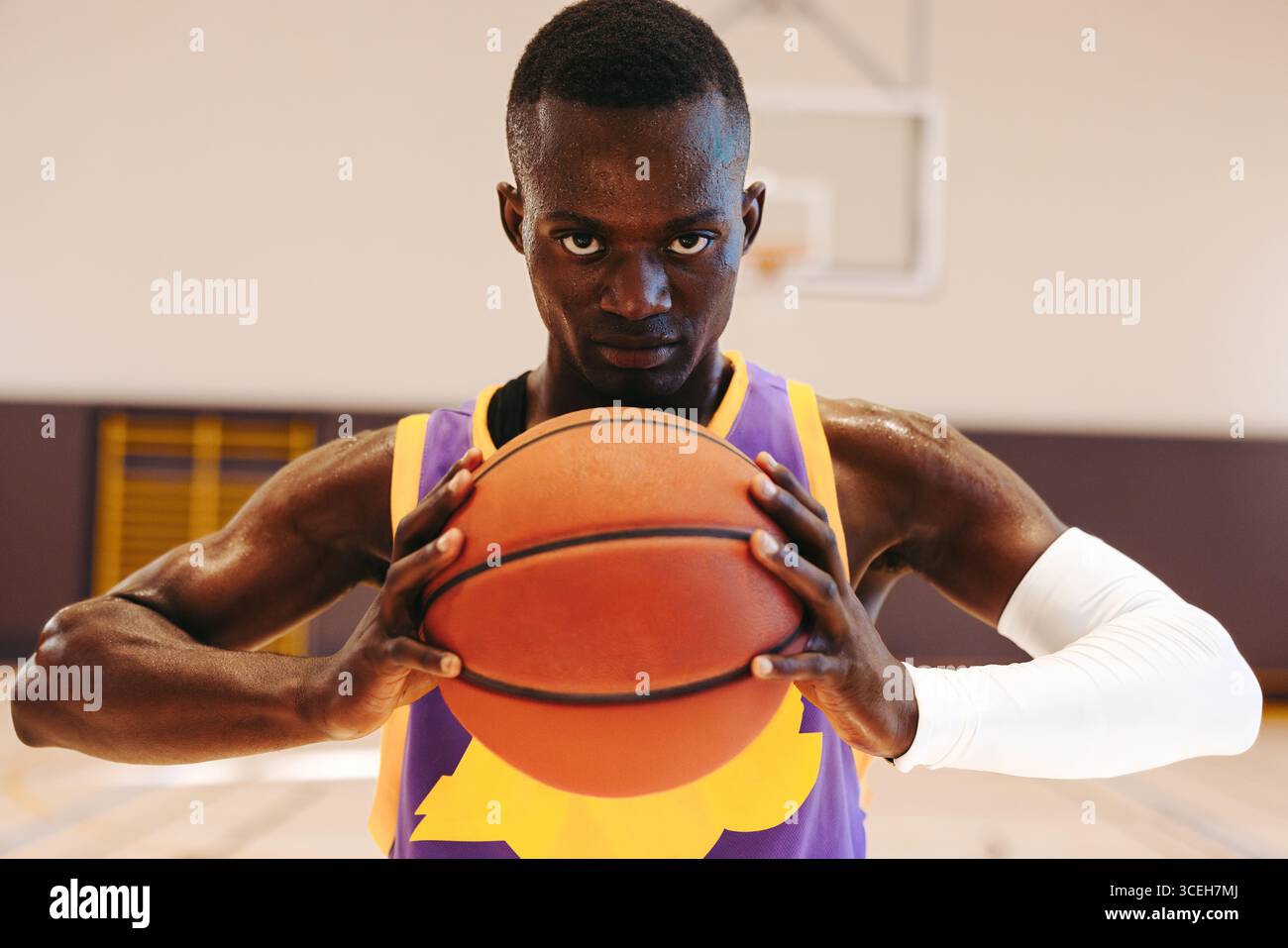 With a calm but serious look, a basketball player holds the ball in ...