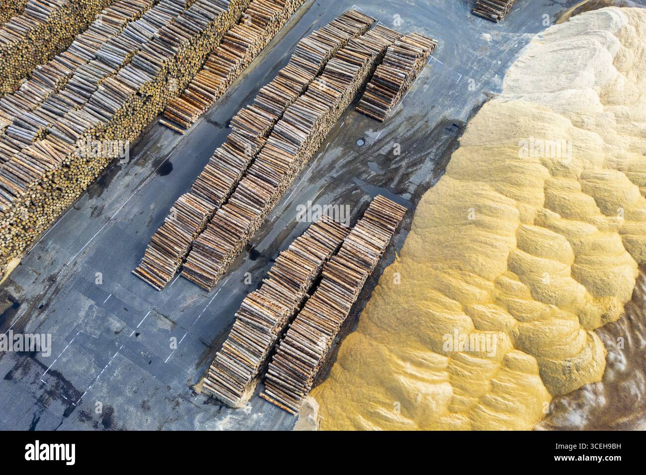 Aerial view of stacks of logs and piles of wood chips create an ...