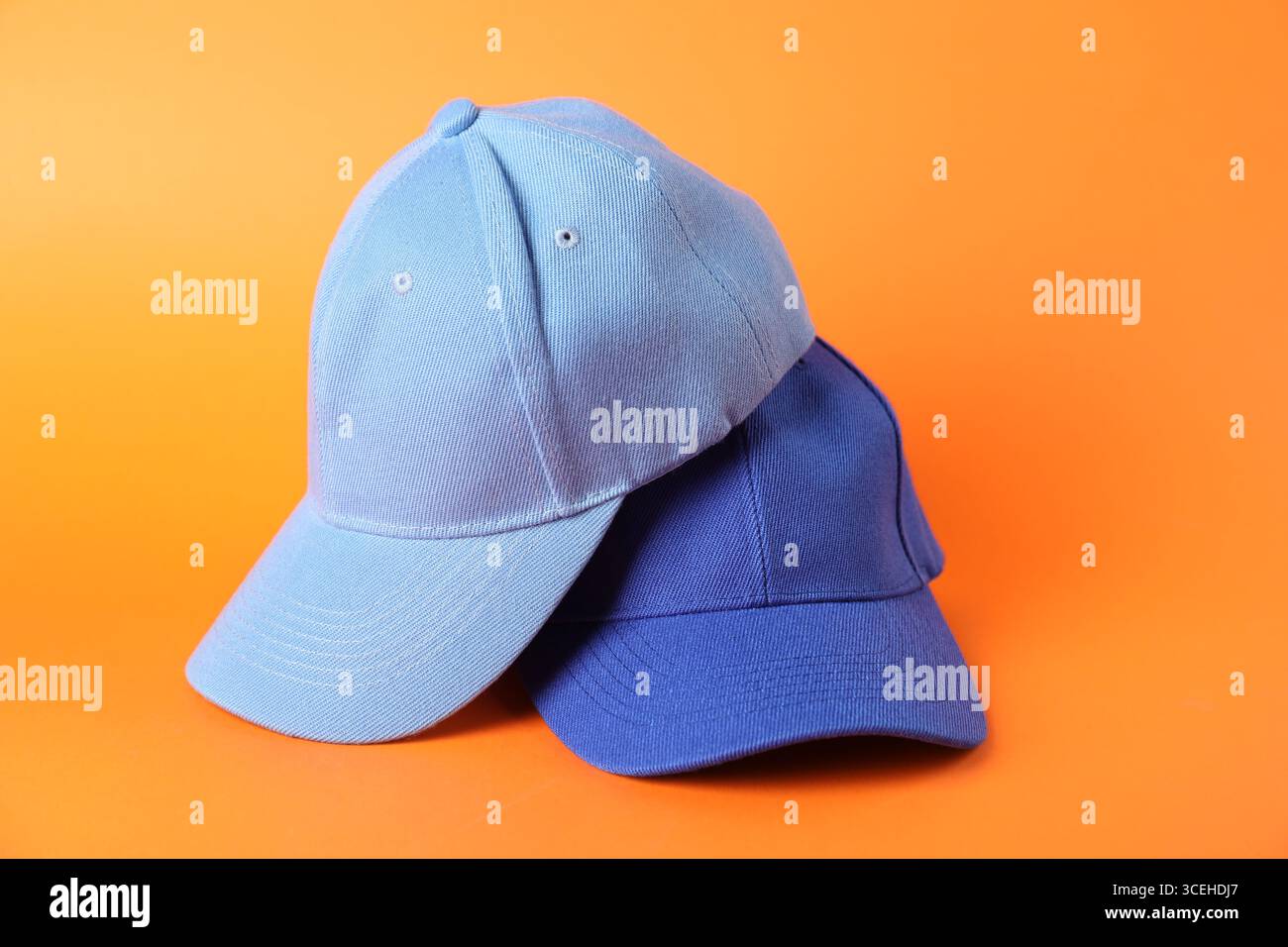 Stylish baseball caps on orange background, closeup. Mockup for design ...