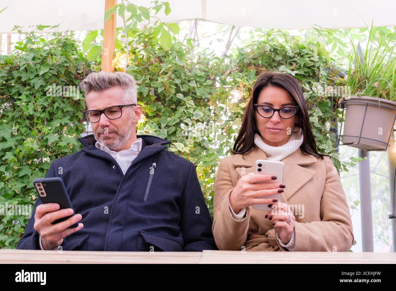 Couple using smartphones at café Stock Photo - Alamy