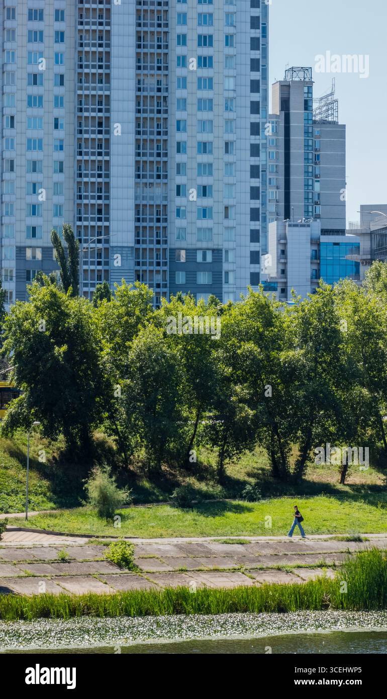Woman is enjoying a leisurely stroll along a paved path by the river ...