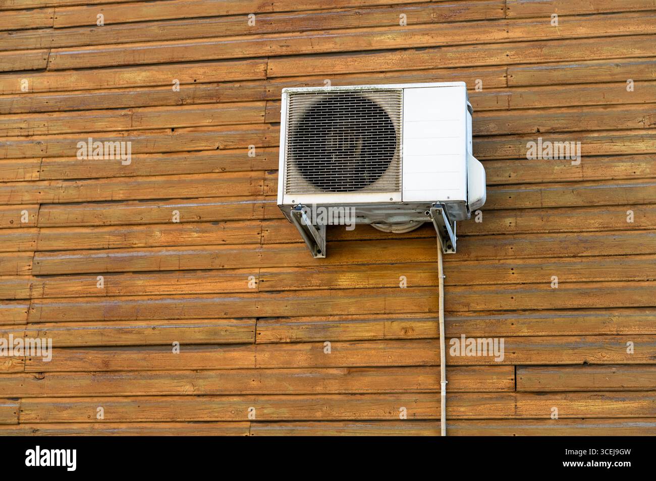Air conditioner unit mounted on wall of old wooden house with aged ...