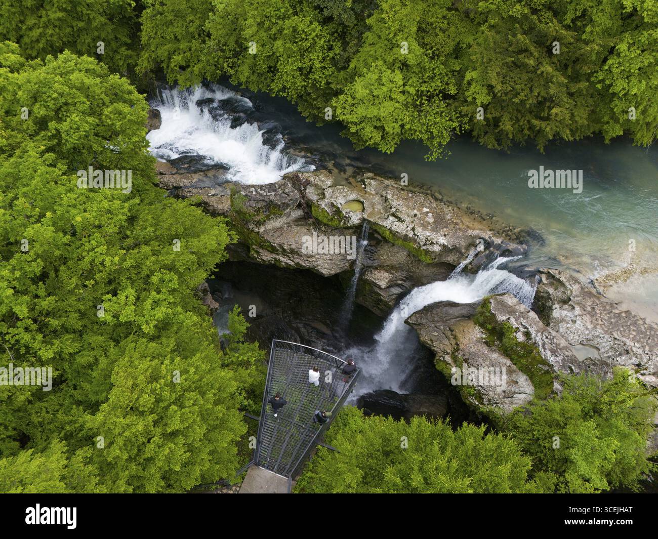 View over a waterfall in a tree-lined river, with a platform, aerial ...