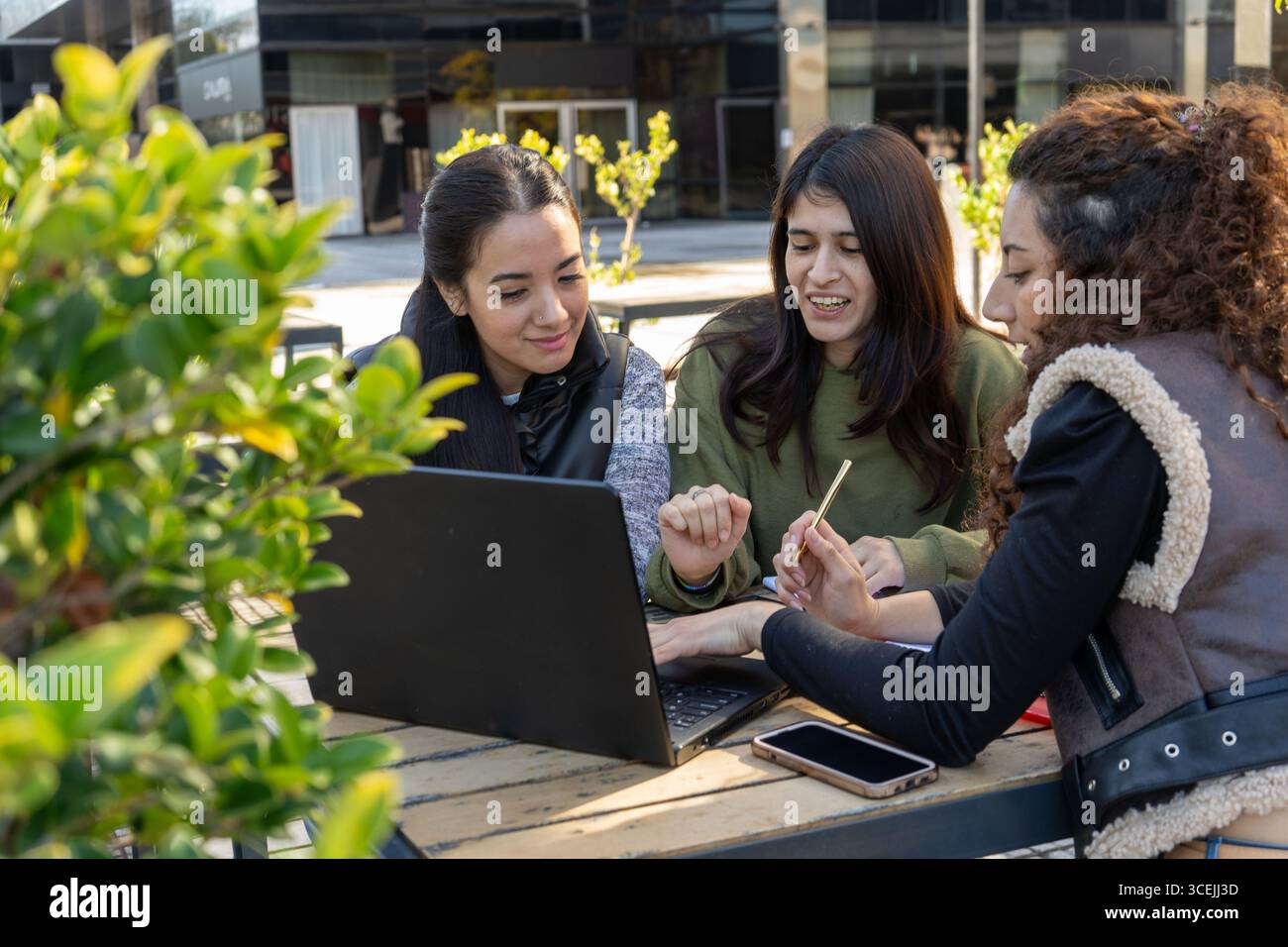 Three university students working together on a project using a laptop ...