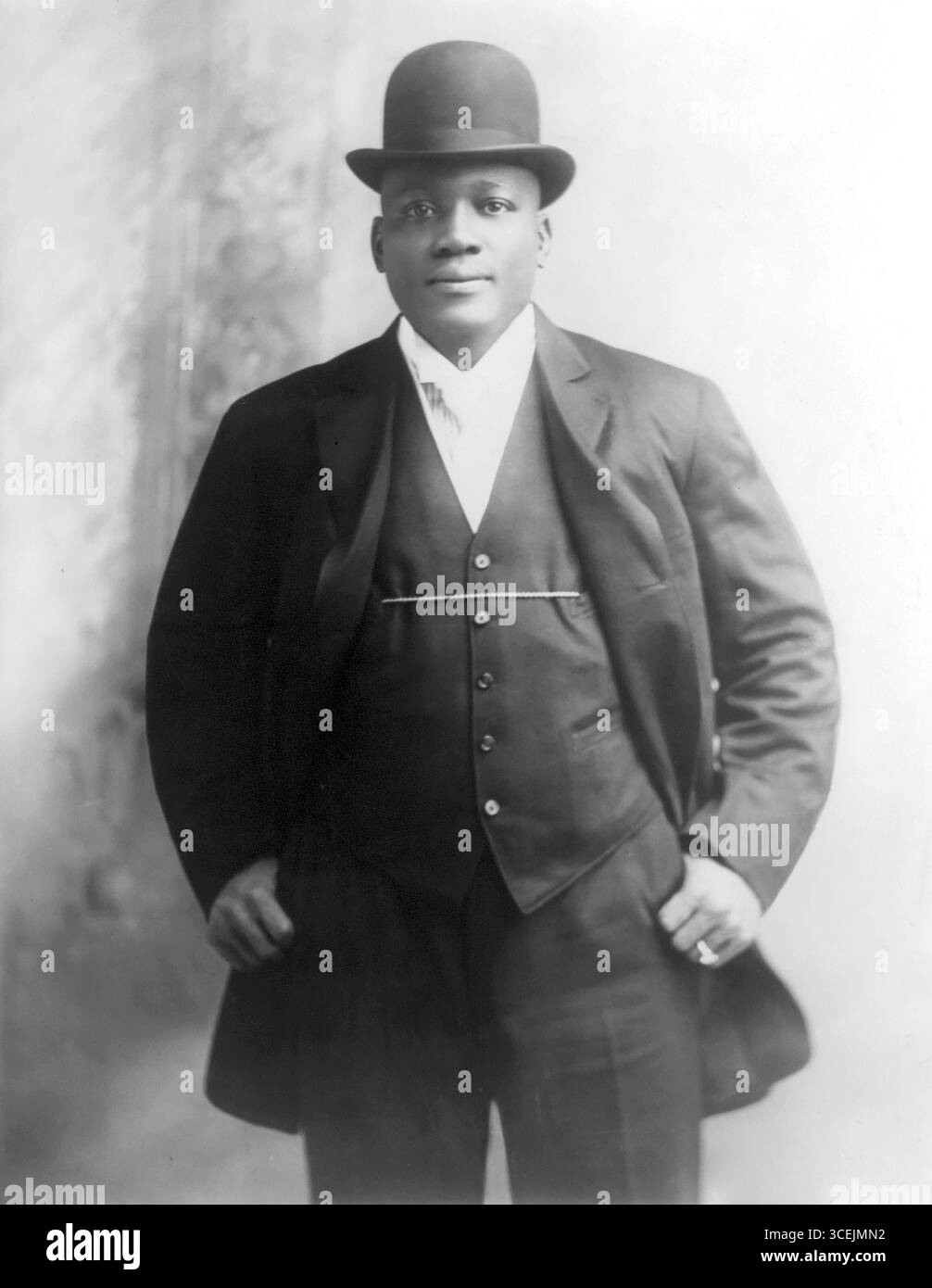 Boxer Jack Johnson, wearing bowler hat and vested suit; thumbs in ...